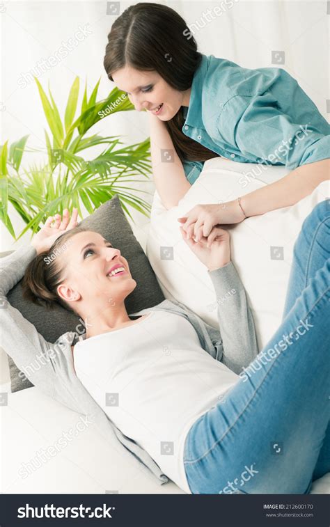 Loving Lesbian Couple Flirting And Holding Hands On The Sofa At Home