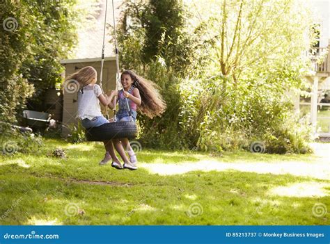 Twee Meisjes Die Samen Op Bandschommeling Spelen In Tuin Stock