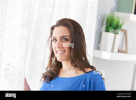 A Woman In Pants Looks Outside By Pulling The Curtains Aside Shielding