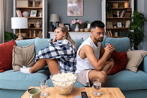 Stressed Young Married Couple Sitting Separately On Different Sides Of