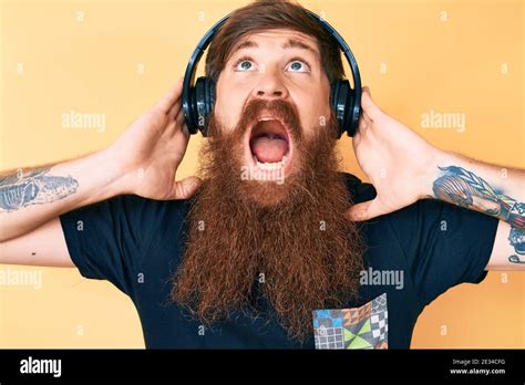 Handsome Young Red Head Man With Long Beard Listening To Music Using