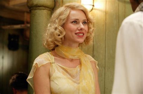 A Woman With Blonde Hair Wearing A Yellow Dress And Smiling At Someone