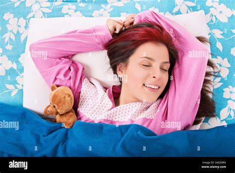 Beautiful Smiling Young Woman In Pink Pajamas Sleeping In Bed With A
