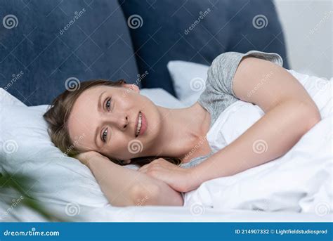 Pretty Smiling Young Woman Lying In Bed And Looking At Camera Stock