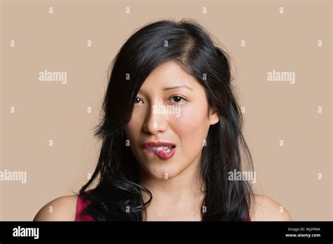 Portrait Of A Beautiful Young Woman Biting Lip Over Colored Background