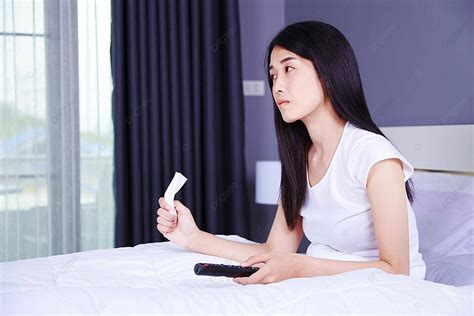 امرأة مضطربة على الفراش في غرفة النوم تتدفق الدموع على وجهها بينما تحمل