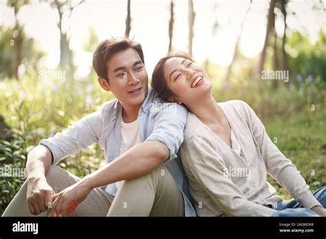 Beautiful Happy Young Asian Couple Sitting On Grass Talking Chatting