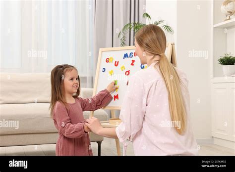 Mom Teaching Her Daughter Alphabet With Magnetic Letters At Home Stock