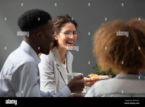 Excited Woman Laughing At Funny Joke Eating Pizza With Colleagues