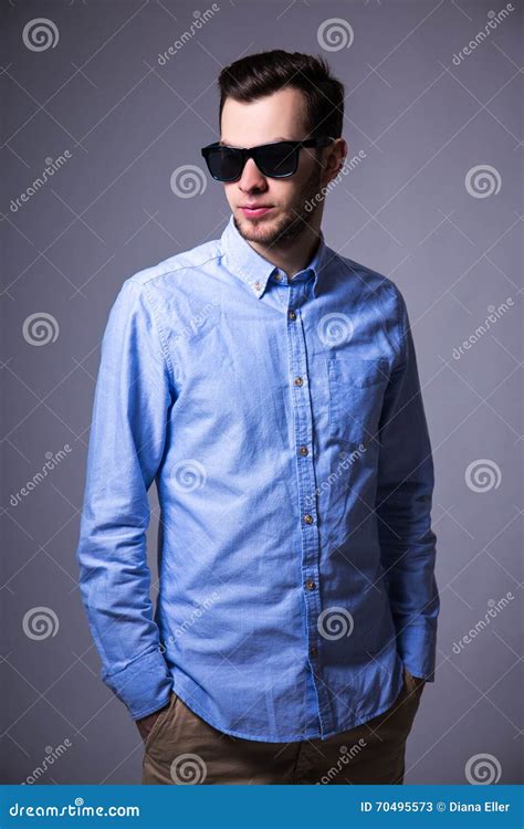 Portrait Of Young Handsome Man In Sunglasses Posing Over Gray Stock