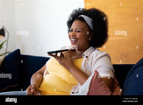 Happy Plus Size African American Woman Sitting On Sofa Talking On