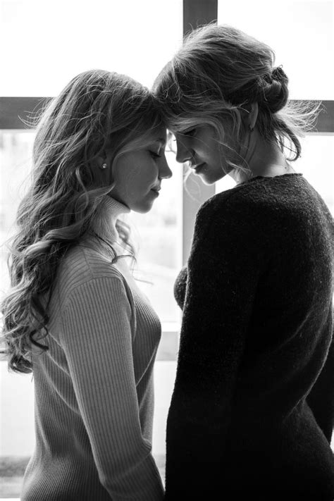 Two Women Standing Next To Each Other In Front Of A Window With Their