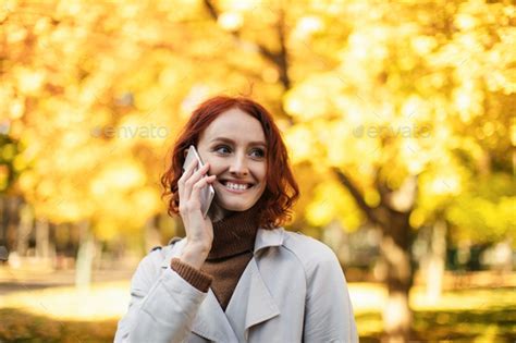 Cheerful Caucasian Millennial Red Haired Lady In Raincoat Calls By