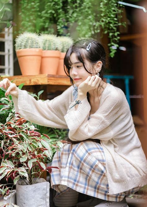 A Woman Kneeling Down Next To Potted Plants