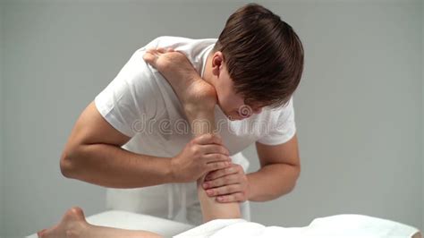 Male Masseur With Strong Hands Massaging Lower Part Of Leg To Young