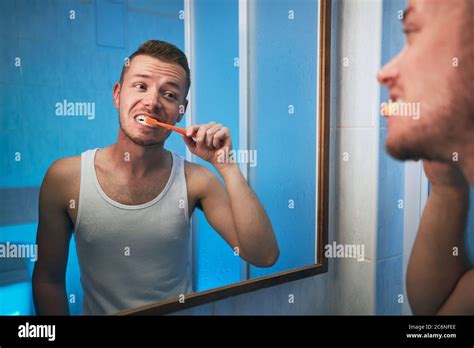 Morning Hygiene Routine Man Brushing Teeth And Looking In Mirror Of