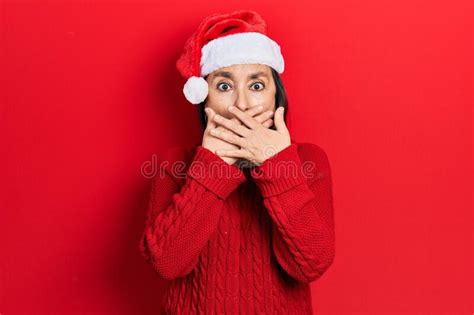 Middle Age Hispanic Woman Wearing Christmas Hat Shocked Covering Mouth