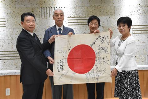 「キセキ遺留品返還プロジェクト」のスタッフ（右から2人目）から、日章旗を手渡された北井和夫会長（左から2人目）＝29日、神戸市 空襲と震災