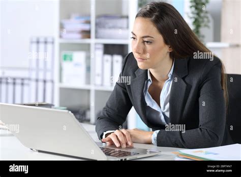 Distracted Executive Woman With Laptop Looking Away Sitting On Her Desk
