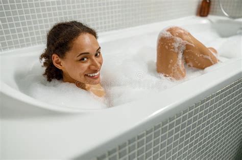 Smiling Afro American Woman Takes Bubble Bath In Bathtub Spa Wellness