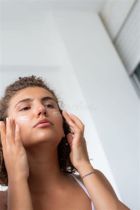 Beautiful Young Woman Applying Cosmetic Cream Treatment On Her Face