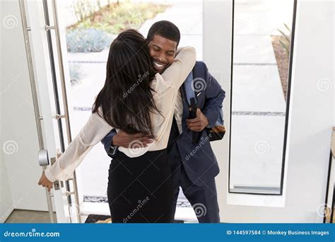 Woman Greeting And Hugging Businessman Husband As He Returns Home From