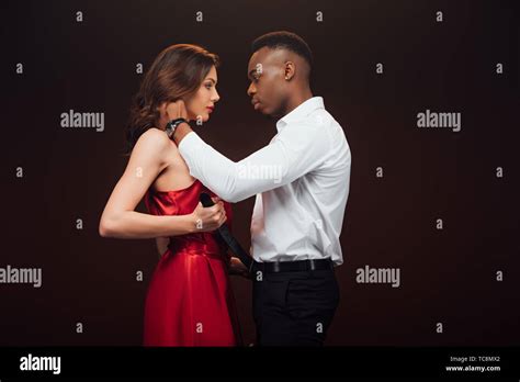 Beautiful Interracial Couple In Formal Wear Embracing And Looking At