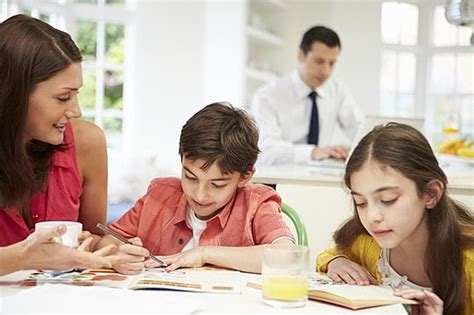 أمي تساعد الأطفال في أداء الواجبات المنزلية حيث يعمل الأب في الخلفية