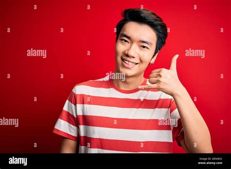 Young Handsome Chinese Man Wearing Casual Striped T Shirt Standing Over