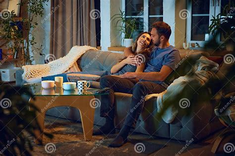 Loving Young Couple Man And Woman Sitting On Sofa In Evening At Home