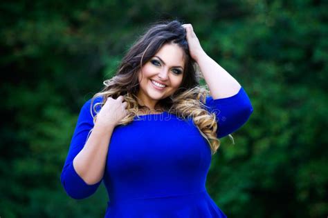 Plus Size Fashion Model In Blue Dress With A Deep Neckline Outdoors