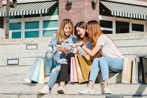 امرأة آسيوية جميلة جذابة تستخدم هاتفًا ذكيًا بينما تتسوق امرأة آسيوية