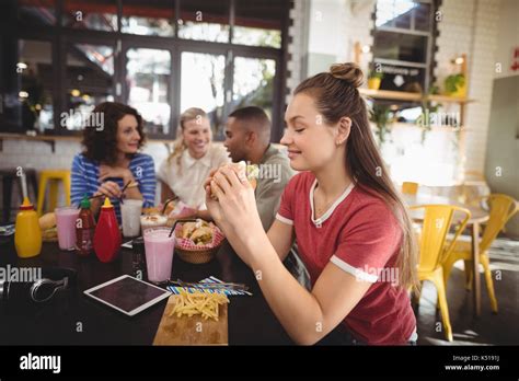Hermosa Joven Comiendo Hamburguesas Con Amigos Mientras Está Sentado A