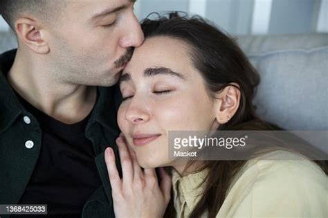 Affectionate Man Kissing Girlfriends Forehead In Bedroom At Home High