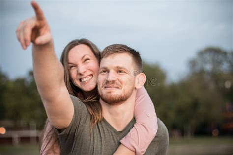 Man Carries His Girlfriend On His Back And Pointing To Something Nice