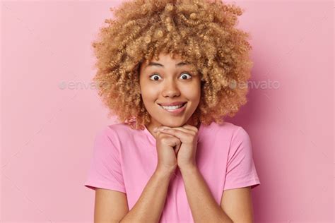 Portrait Of Surprised Young Woman With Curly Bushy Hair Keeps Hands