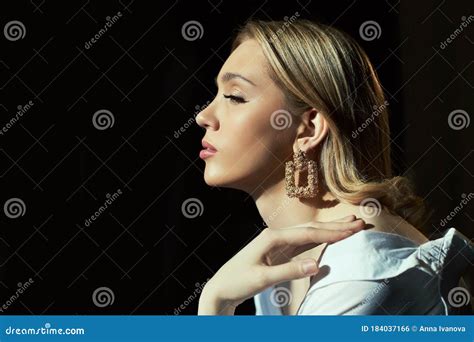 Blonde Women With Jewelry Earrings In Their Ears In The Rays Of The