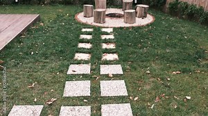Tree stumps around fire pit with smoke rising from the burning logs. Camping area, cozy backyard fire pit