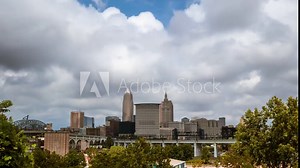 Cleveland, Ohio time-lapse of the downtown skyline with dramatic clouds passing by. Subway train passes on the rapid track in the foreground with the terminal tower as a backdrop.
