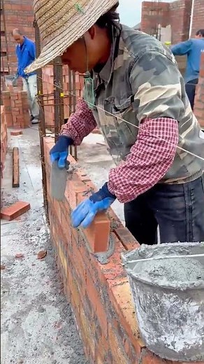 Bricklayer carefully applying mortar and placing red bricks to construct a sturdy wall structure