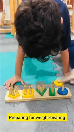 This video clip is from our Occupational therapy session. In a supported wheelbarrow position, the child bears full body weight through the palms and hands, helping to build upper body strength, shoulder stability, and core control. Chair support is used to maintain proper alignment while encouraging safe and effective weight-bearing. While maintaining this position, the shape sorter activity adds a cognitive and fine motor component, improving hand-eye coordination, attention, and problem-solvi