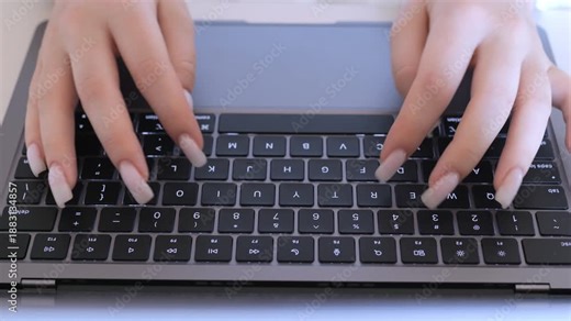 Woman is typing on a laptop keyboard. She is using her fingernails to type. The keyboard has a number pad and a space bar