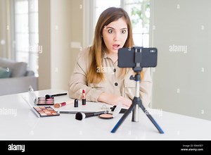Beautiful young influencer woman recording make up video tutorial afraid and shocked with surprise expression, fear and excited face Stock Photo - Alamy
