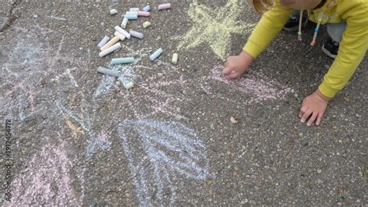 Child paints outdoors. Little girl drawing colored chalk on the asphalt . Creative development of children