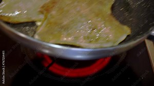 Fried flounder on a metal pan in boiling oil. A cook is frying fish in a home kitchen. Healthy food concept. Food preparation. Slow motion footage.