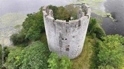 Drone dynamic spiral around castle tower in the lake. Cloughoughter Castle, Ireland