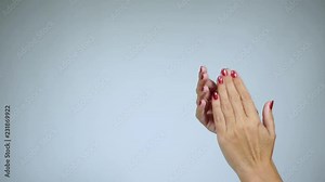 Closeup view of beautiful female hands clapping happily isolated on light background. Fingernails painted with glossy sparkling red gel polish. Real time 4k video footage with copyspace.