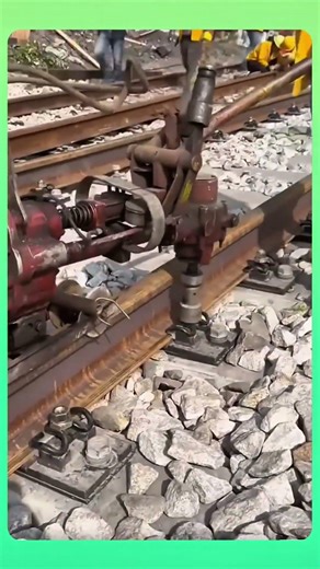 Tightening bolts along the railway track to secure the rails and ensure safe, stable train movement.