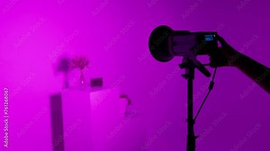 A filmmaker adjusts a professional light stand in a studio, changing its color to suit the indoor shooting set. Stock Video
