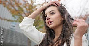 4k. Slow and fast motion. Fancy dressed young business woman in black and white clothes walks along the pass before a modern glass building, turns around, shakes her hair and looks straight into the c